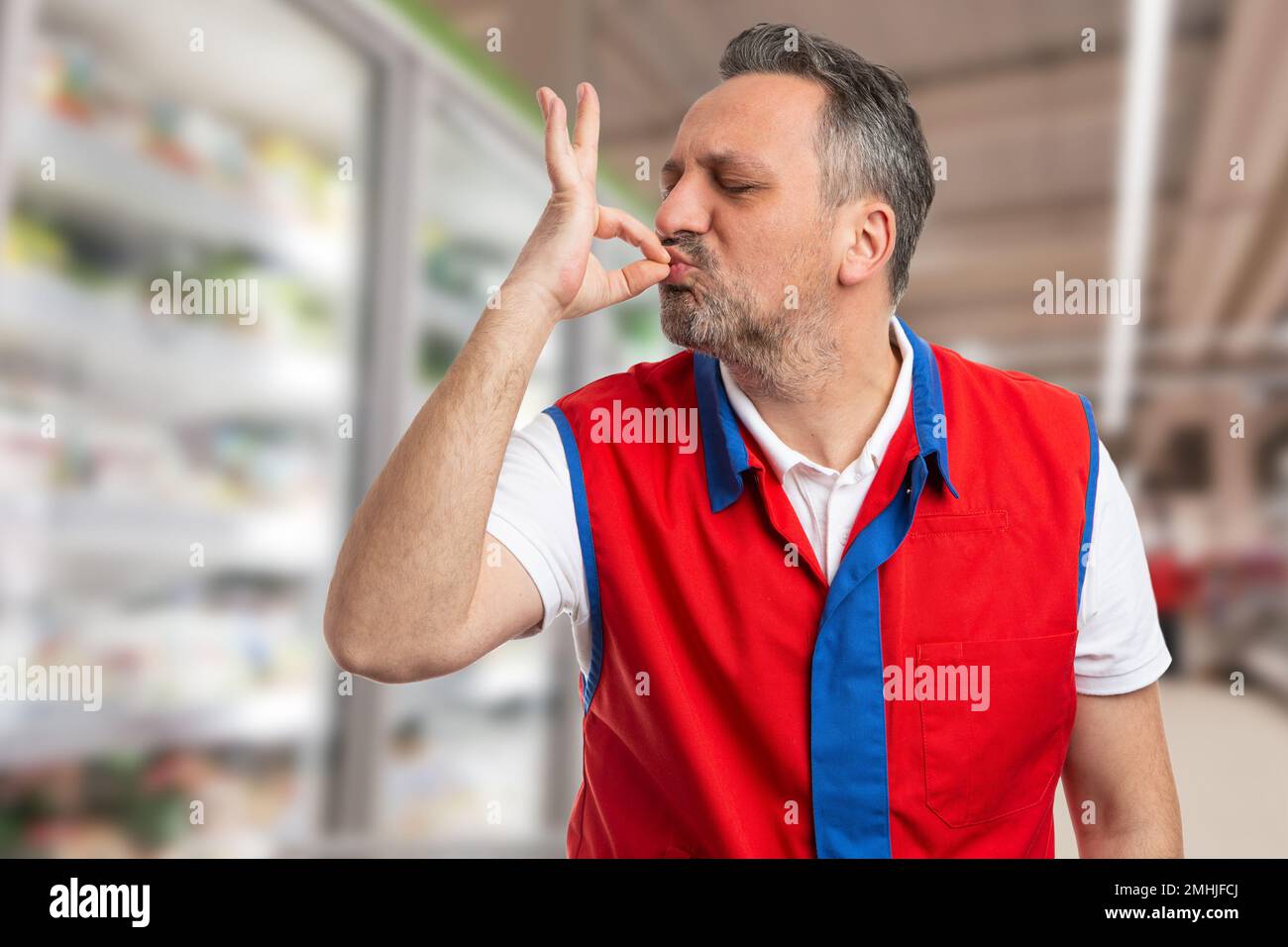 Satisfied worker making okay gesture with fingers on mouth as very good ...
