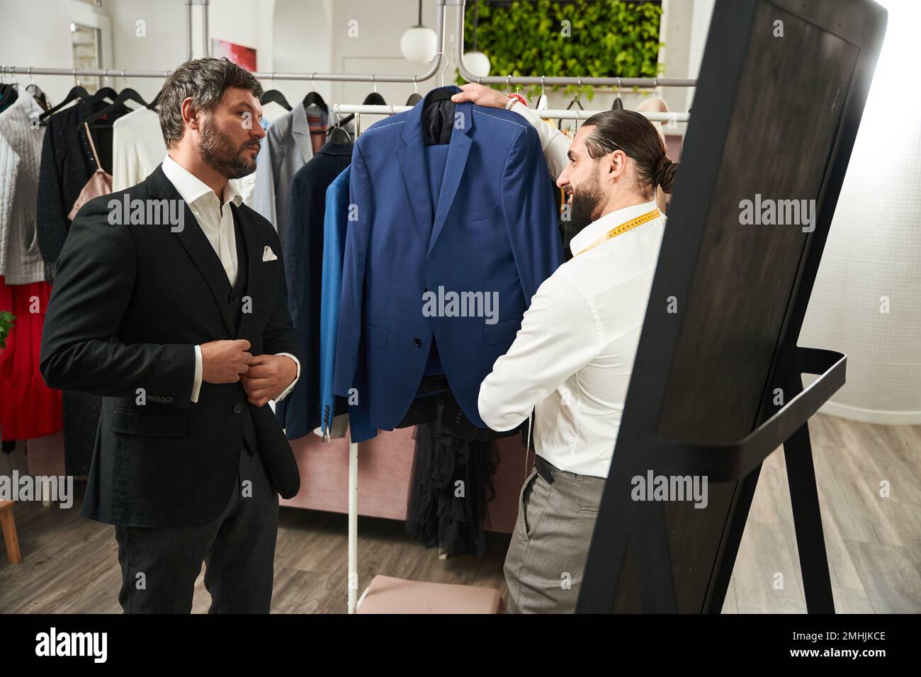 Client trying on new suit in presence of pleased tailor Stock Photo - Alamy