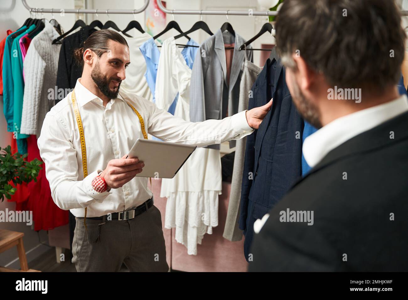 Fashion designer choosing jacket for customer on clothes rack Stock ...