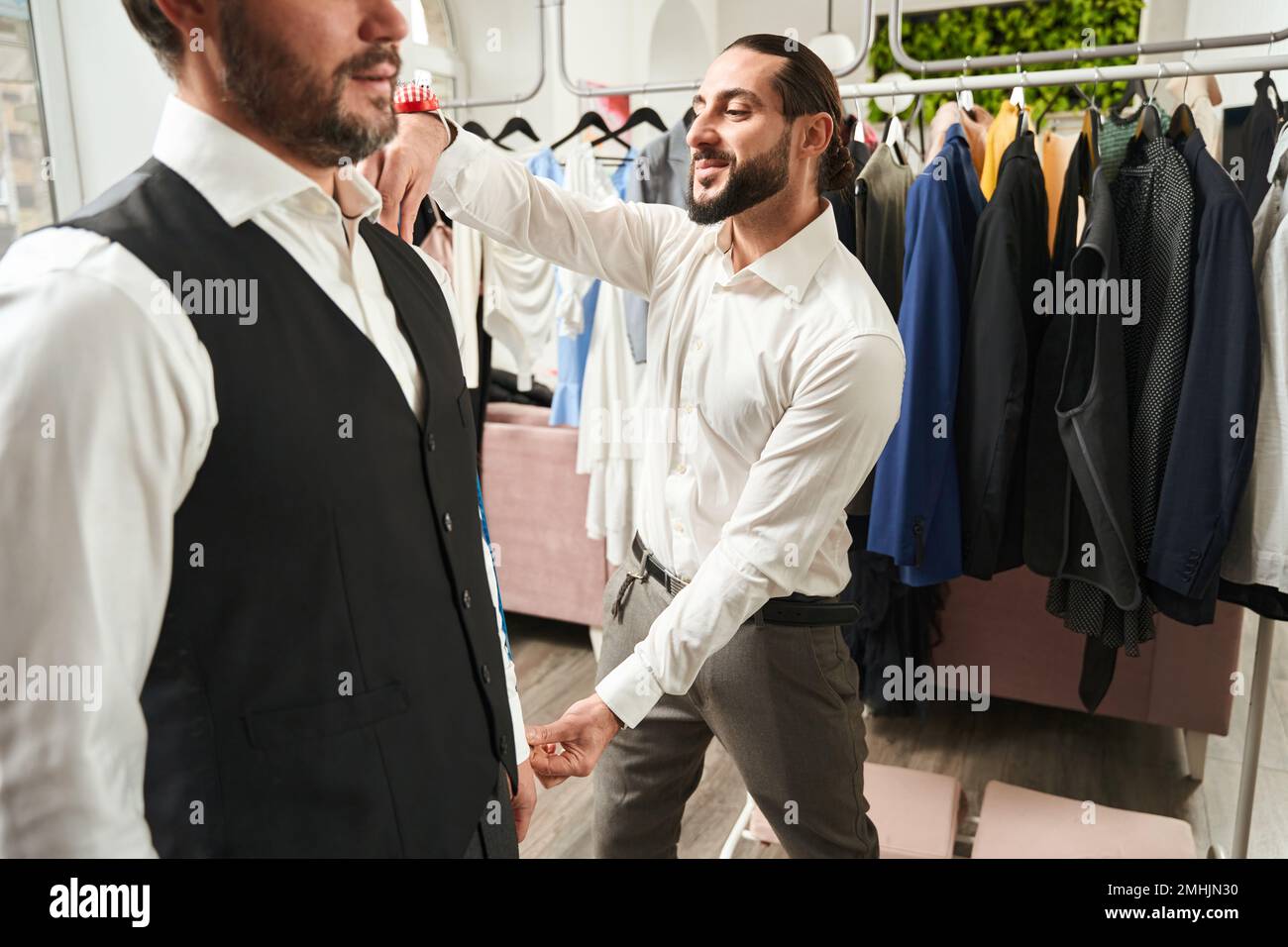 Clothier taking body measurements of adult man using tape measure Stock ...
