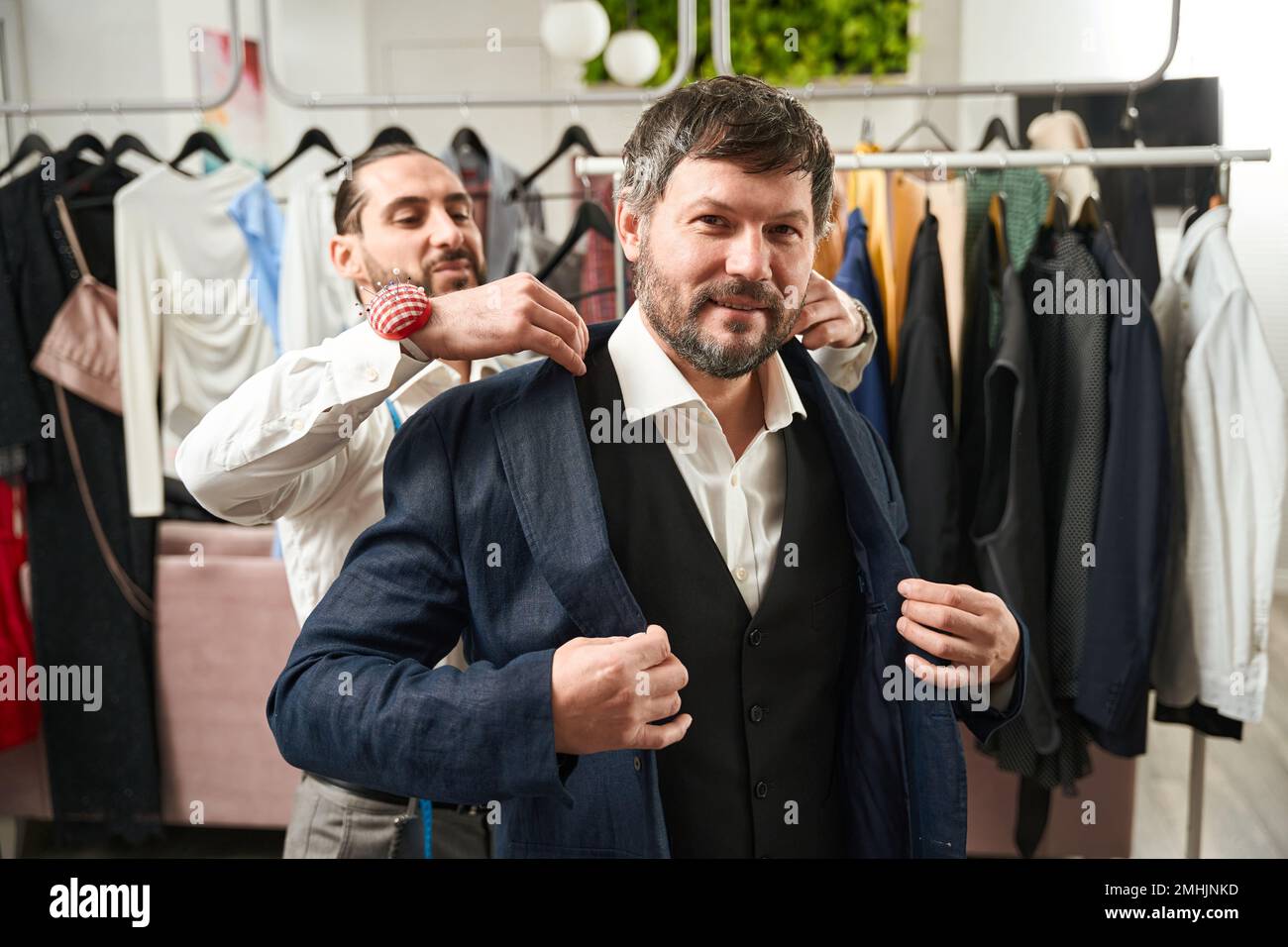 Client trying on jacket aided by tailor Stock Photo - Alamy