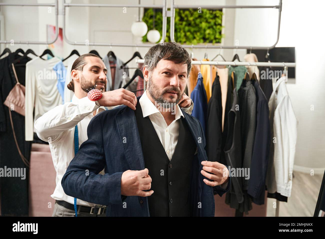 Man putting on jacket in presence of clothier Stock Photo - Alamy