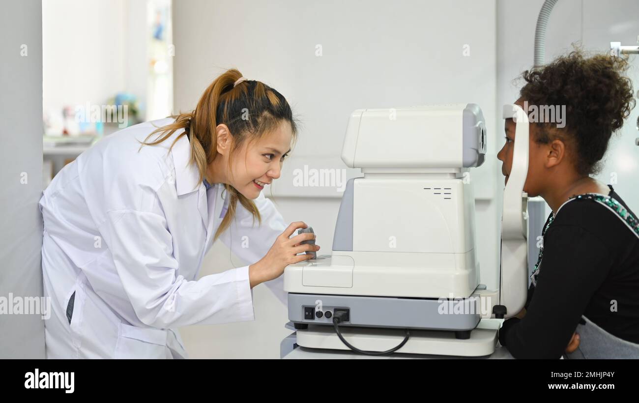 Teenage woman checking eyesight on auto refractor in ophthalmologist ...