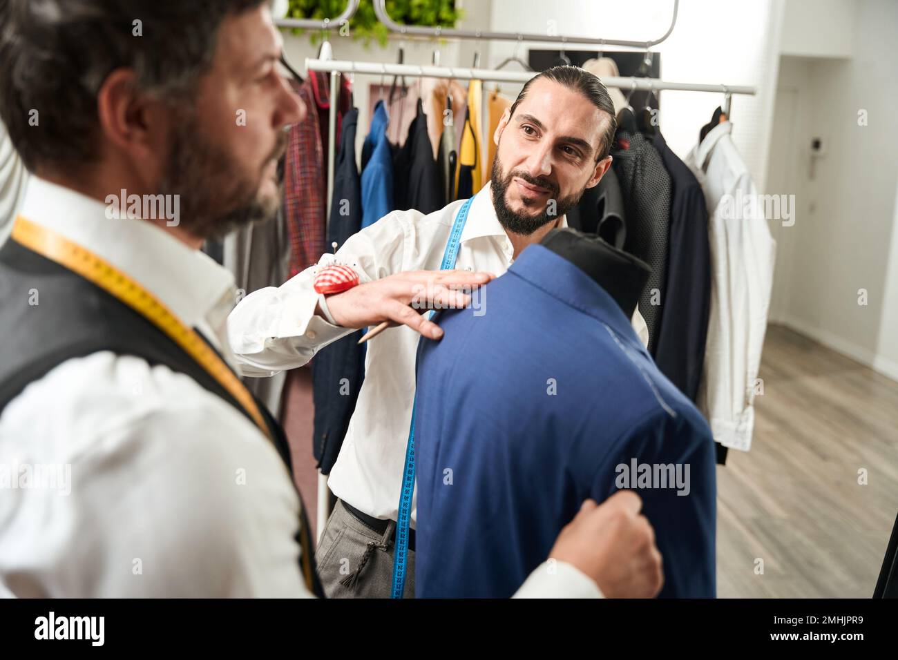 Team of clothiers checking fit of jacket on dummy Stock Photo - Alamy