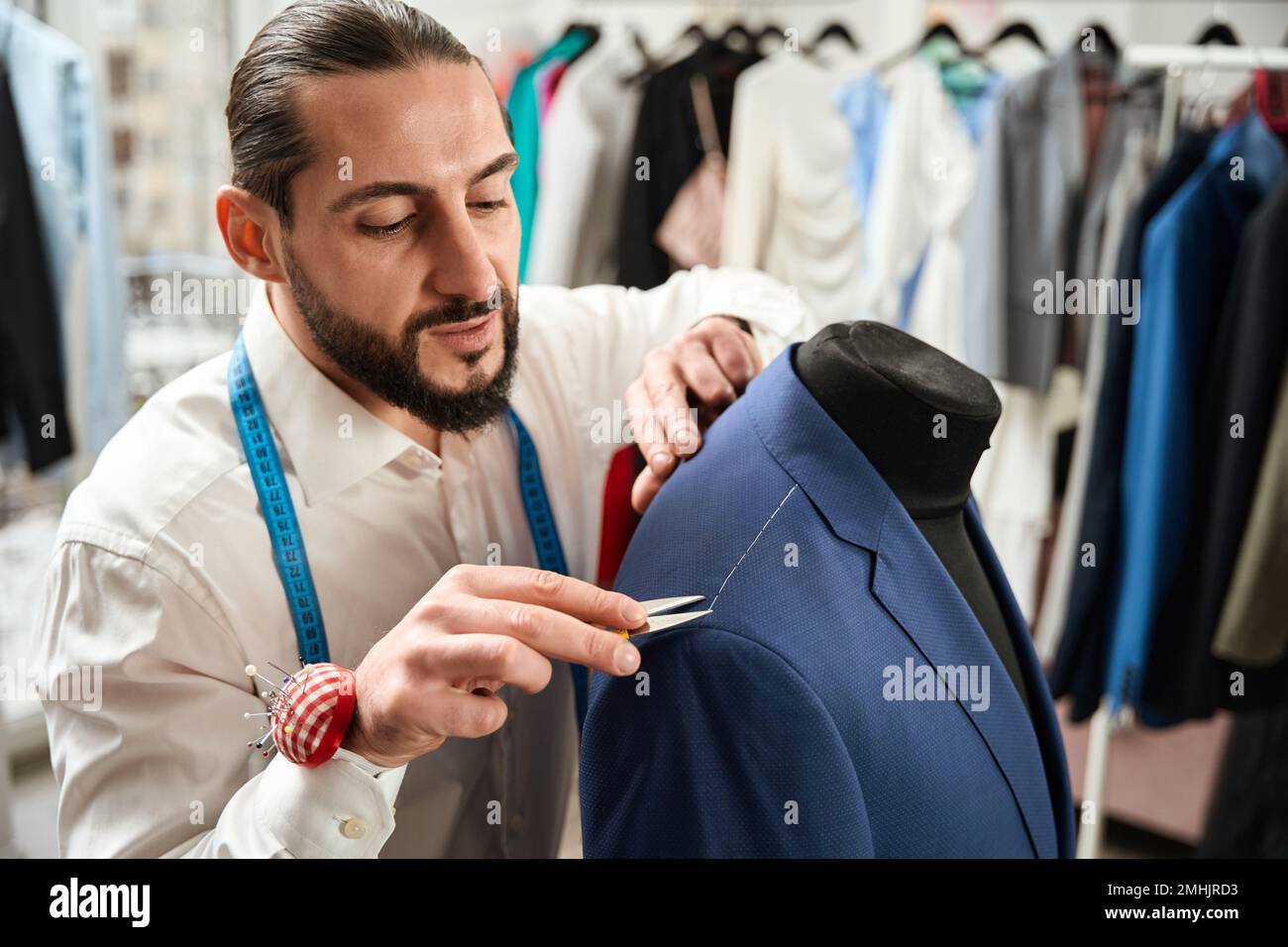 Clothier removing white stitches from client suit Stock Photo - Alamy