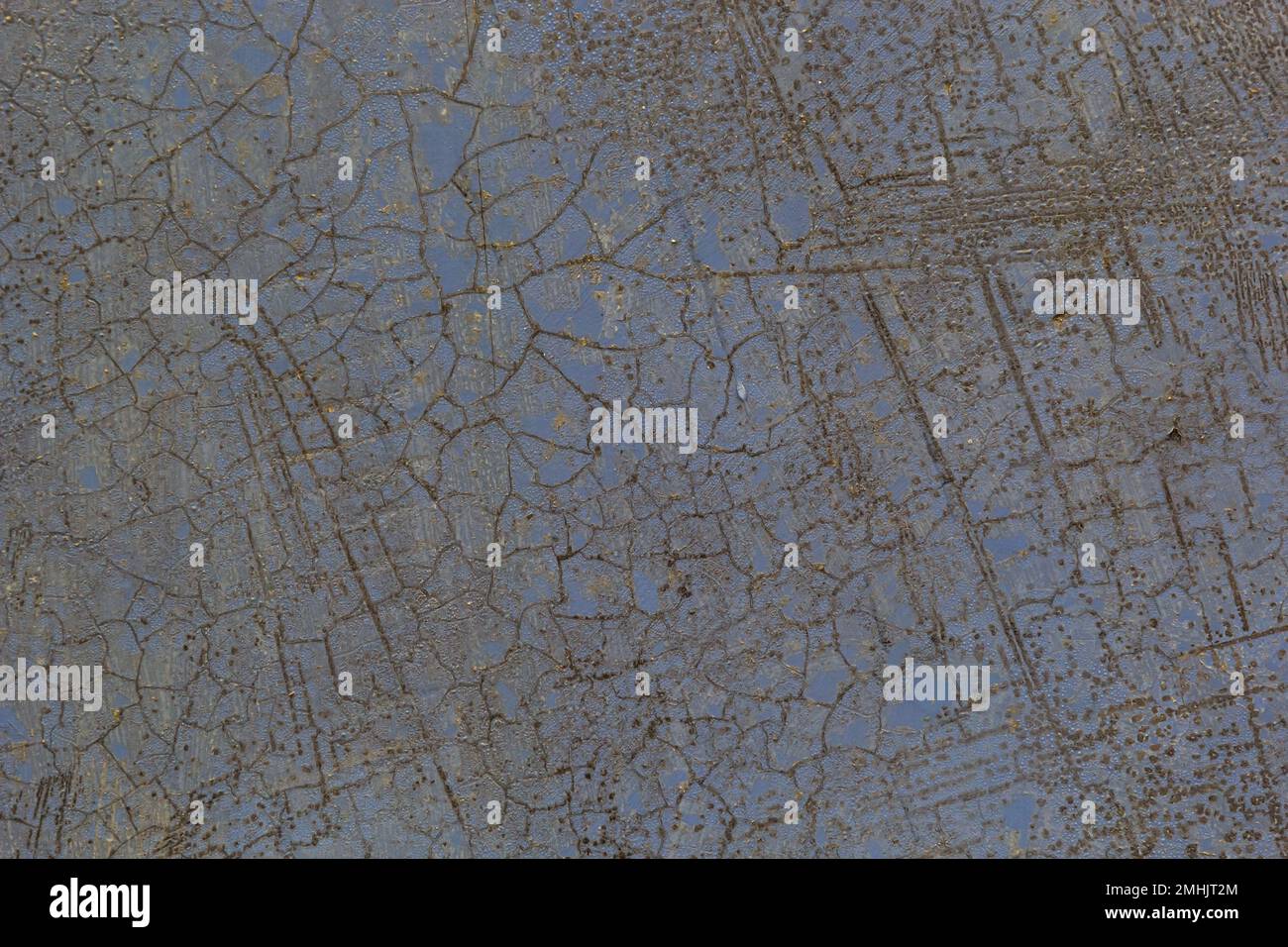 The old metal surface is covered with cracked gray paint with rust ...