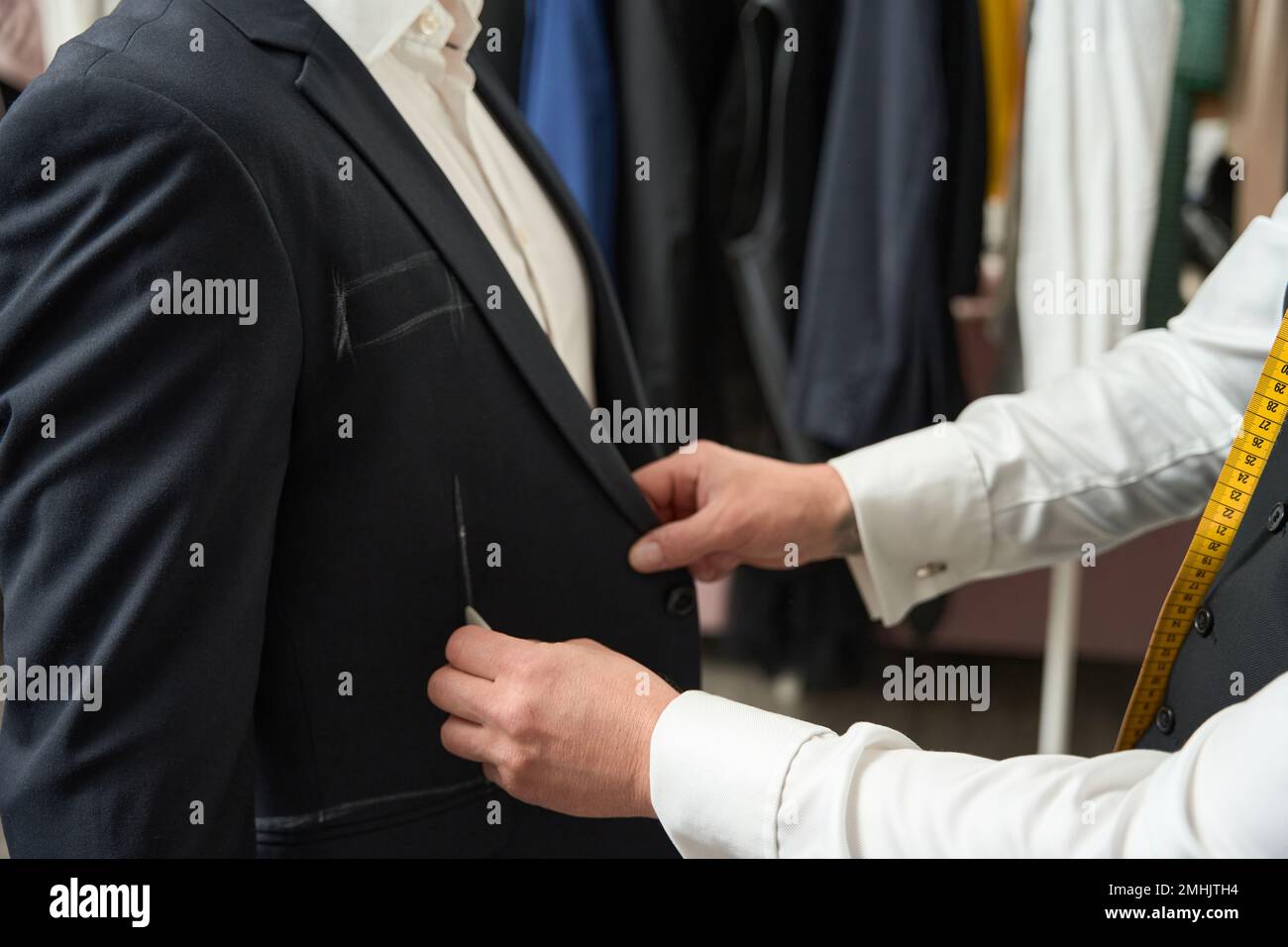 Tailor marking tucks on client jacket during fitting session Stock ...