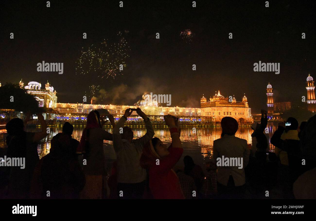 People watch a fireworks display over the illuminated Golden Temple ...