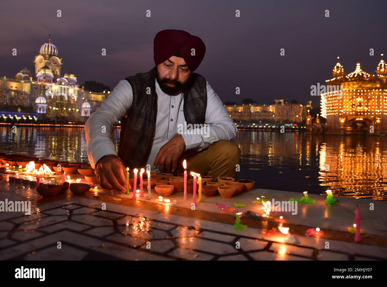 An Indian Sikh lights candles at the Golden Temple illuminated on the ...