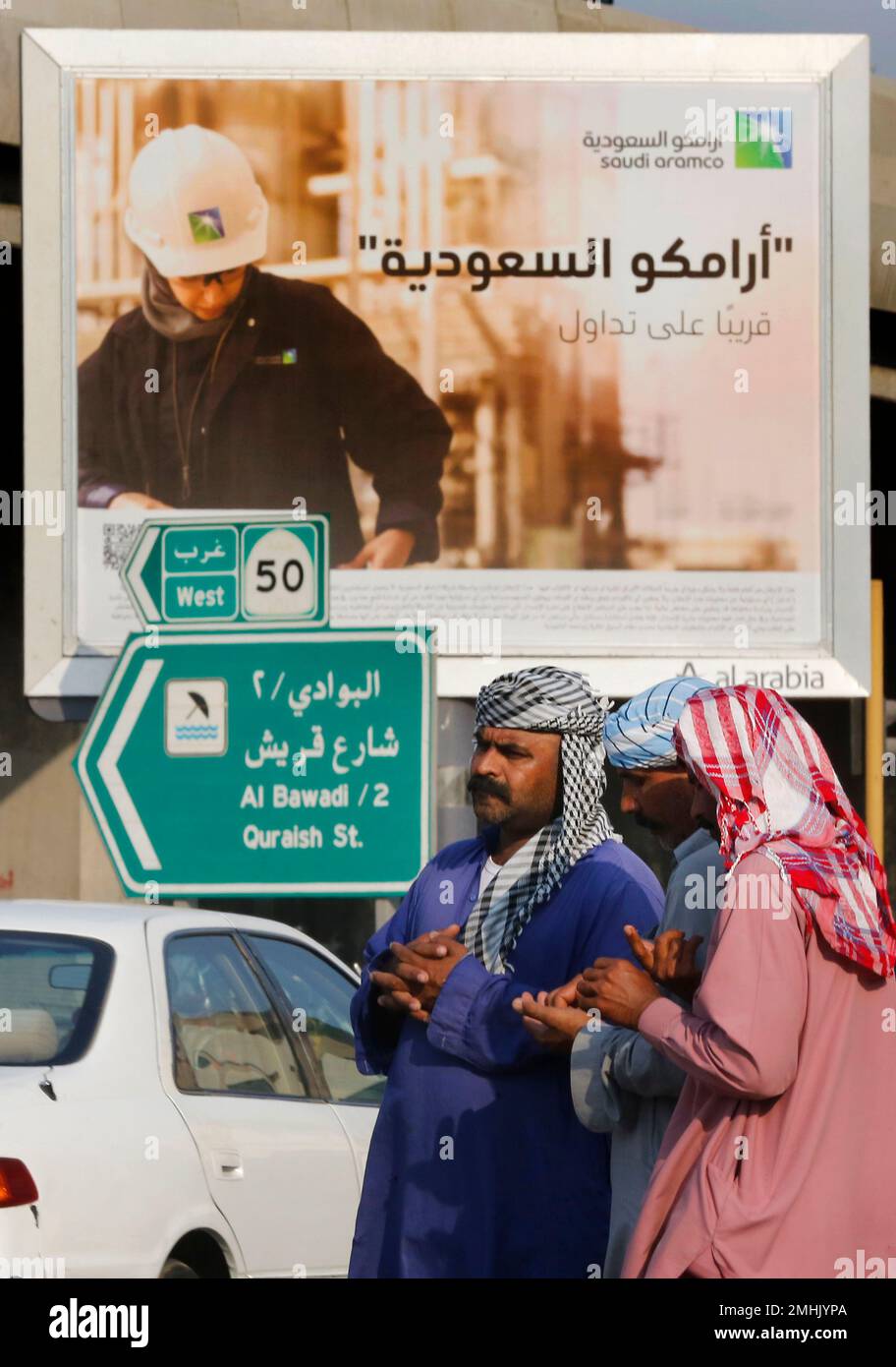 Workers wait in front of a billboard displaying an advertisement for ...