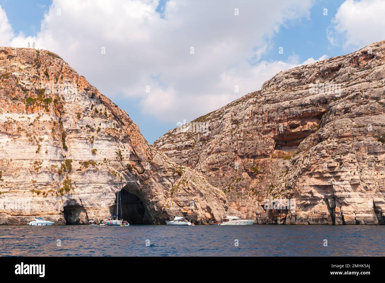 Scenic coastal landscape with yachts and red rocks, Blue Grotto, Malta ...