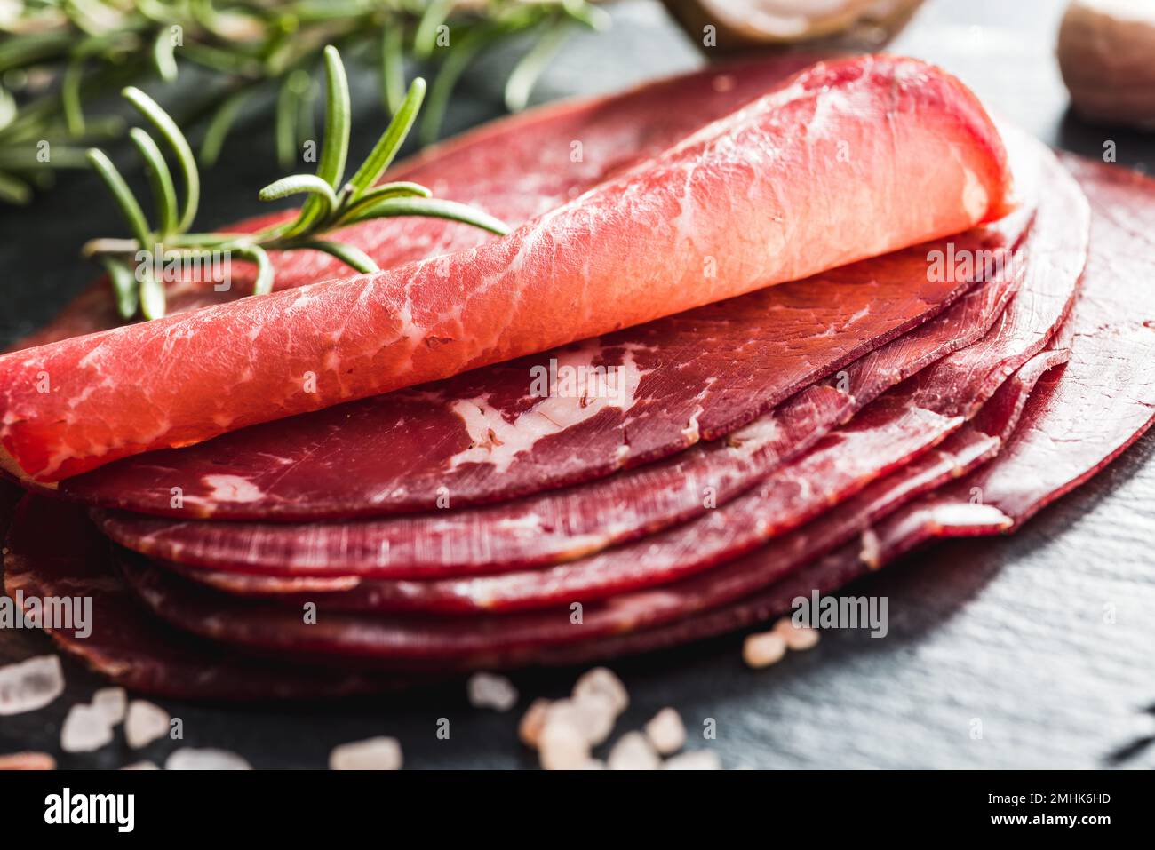 Smoked bresaola. Italian appetizer. Dried beef meat on the black table ...