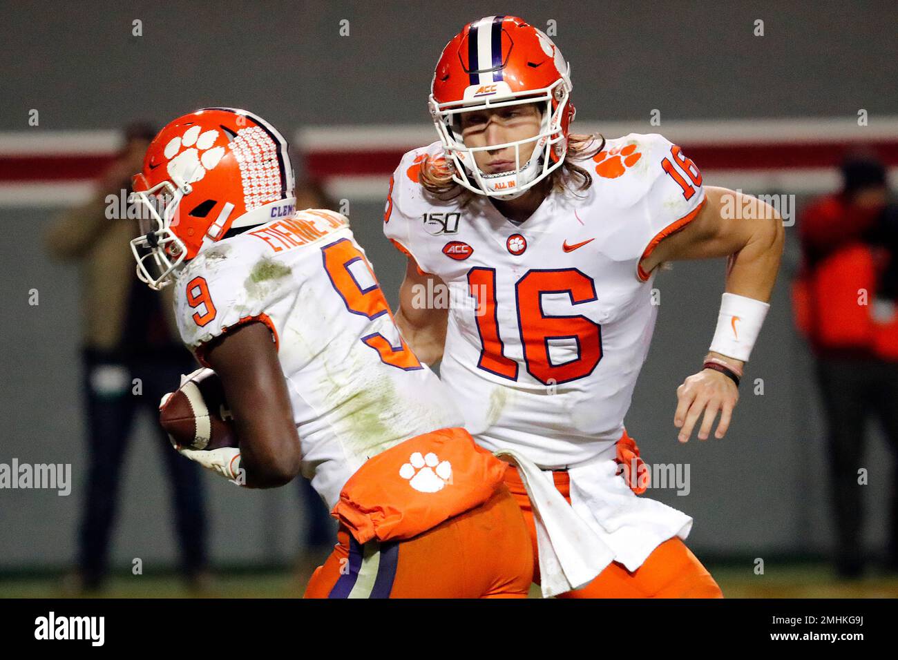 Clemson's Trevor Lawrence (16) hands the ball off to Travis Etienne (9 ...