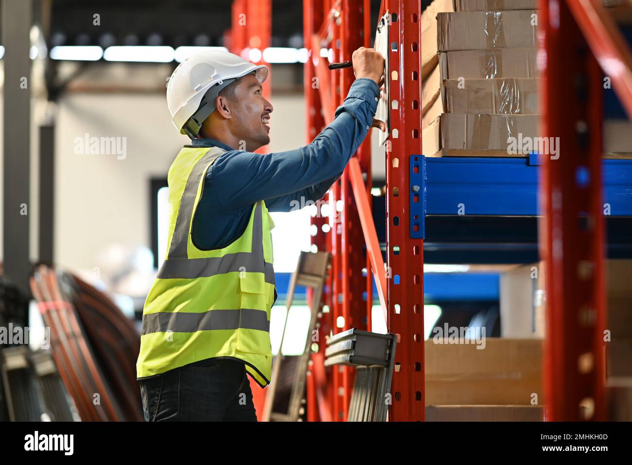 Side view of warehouse worker checking goods and supplies on shelves in ...