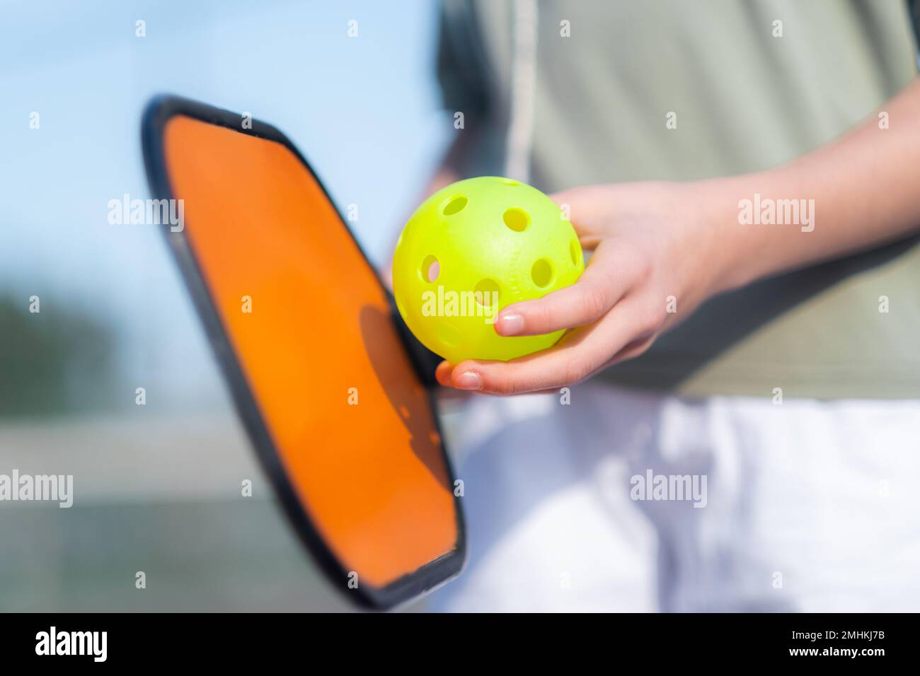 Pickleball paddle and yellow ball close up in children hands, leisure ...