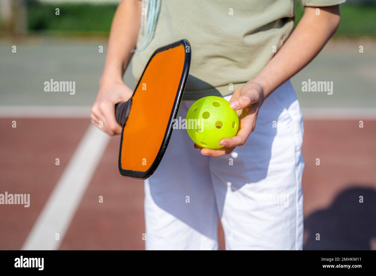 Pickleball paddle and yellow ball close up in children hands, leisure ...
