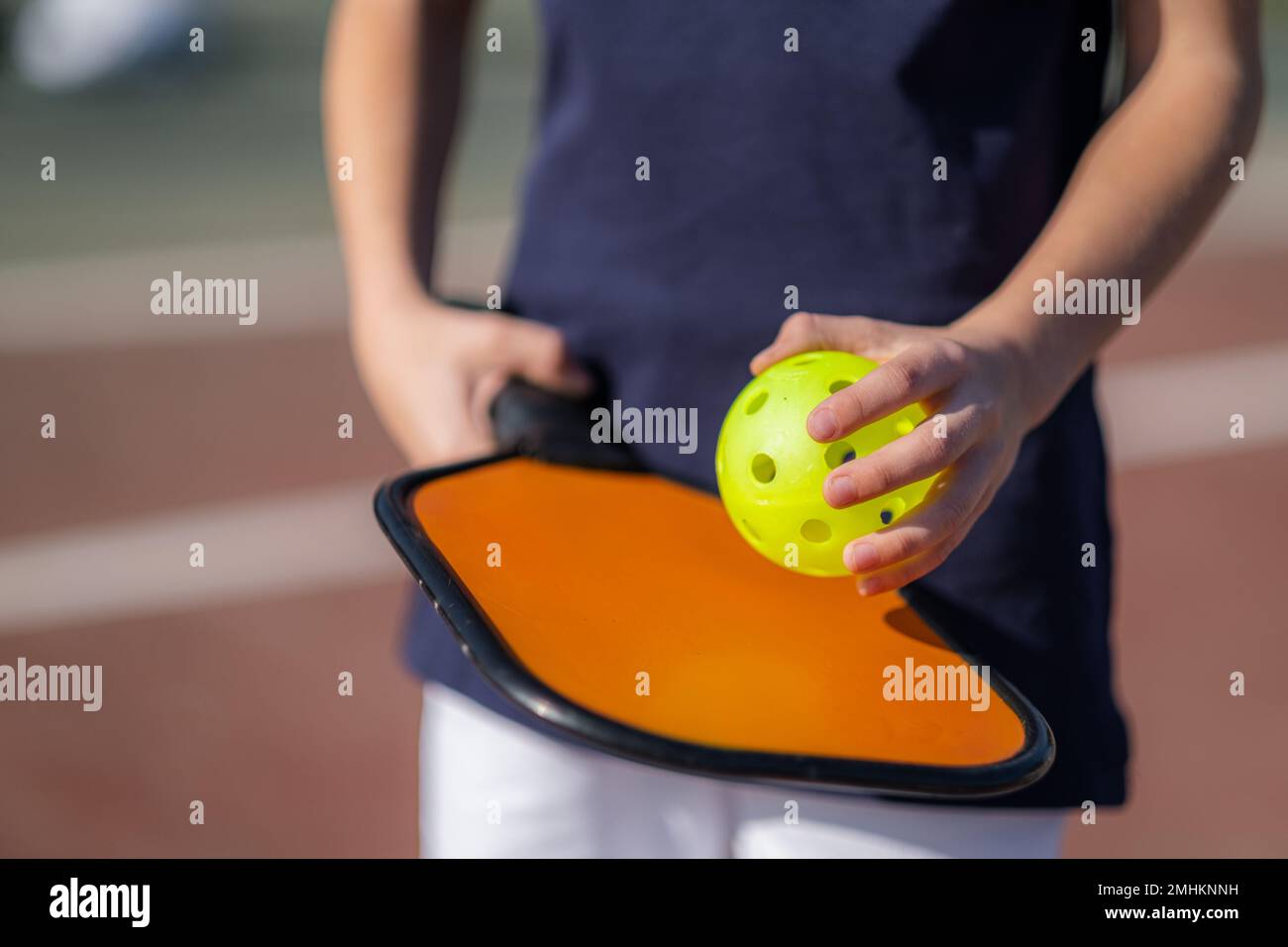 Pickleball paddle and yellow ball close up in children hands, leisure ...