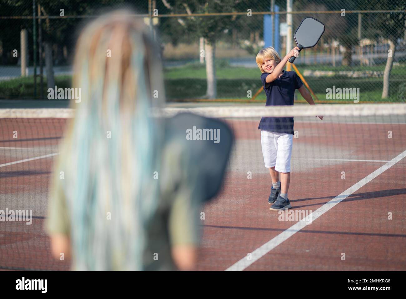 Laughing boy and girl playing pickleball game, hitting pickleball ...