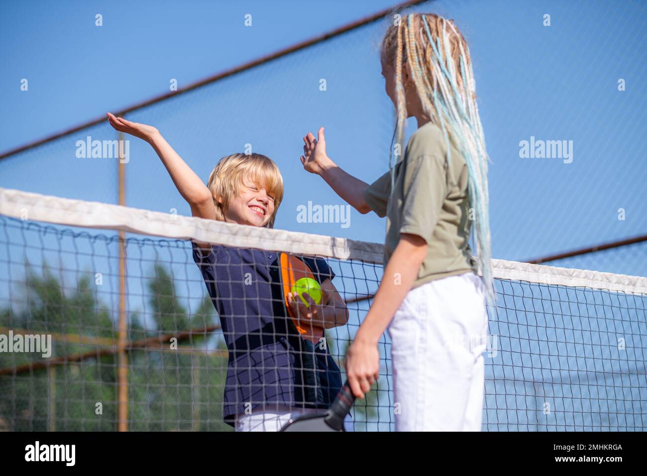 Laughing boy and girl playing pickleball game, hitting pickleball ...