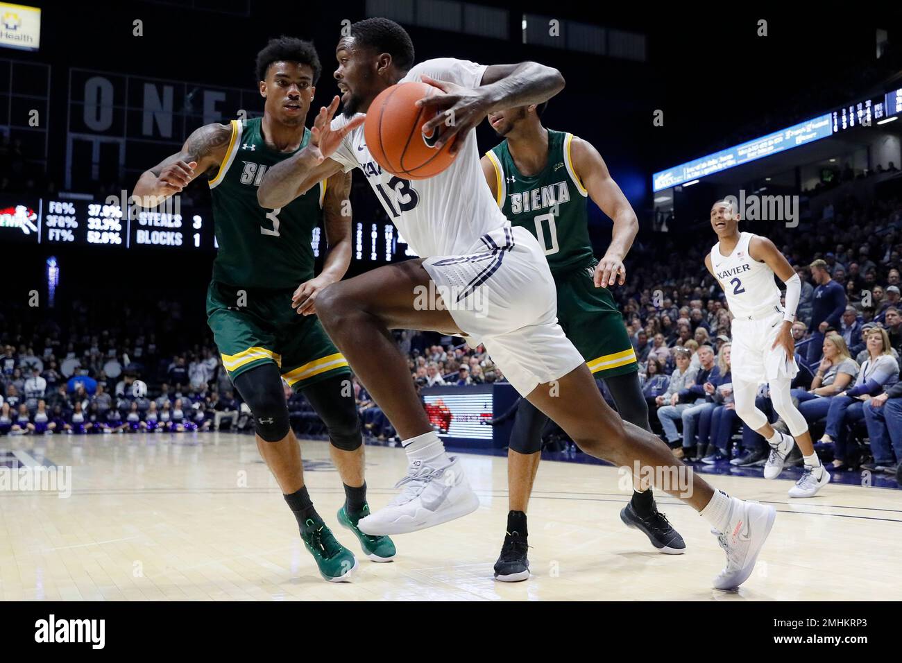Xavier's Naji Marshall (13) drives past Siena's Manny Camper (3) during ...