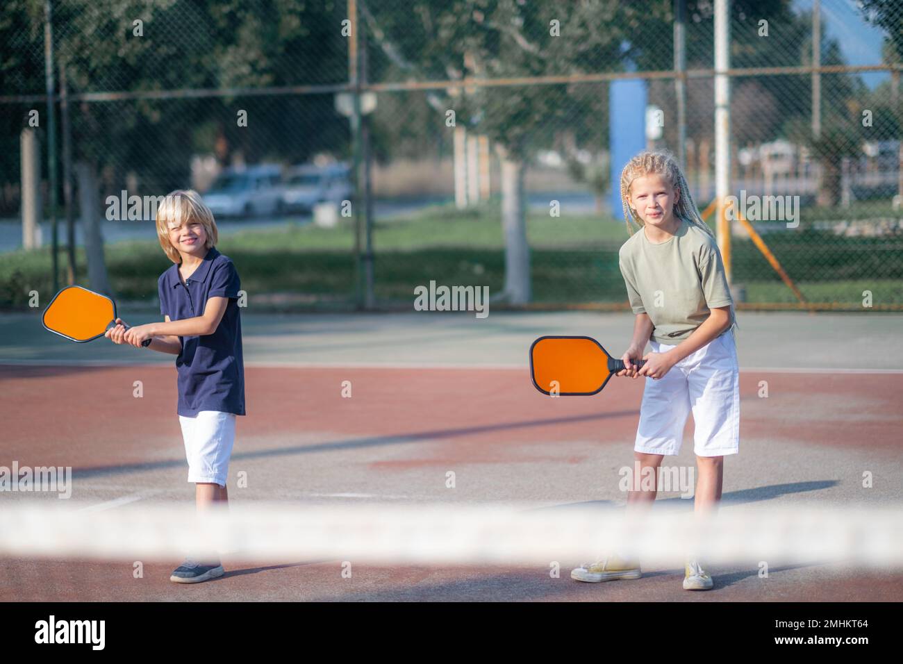 Laughing boy and girl playing pickleball game, hitting pickleball ...