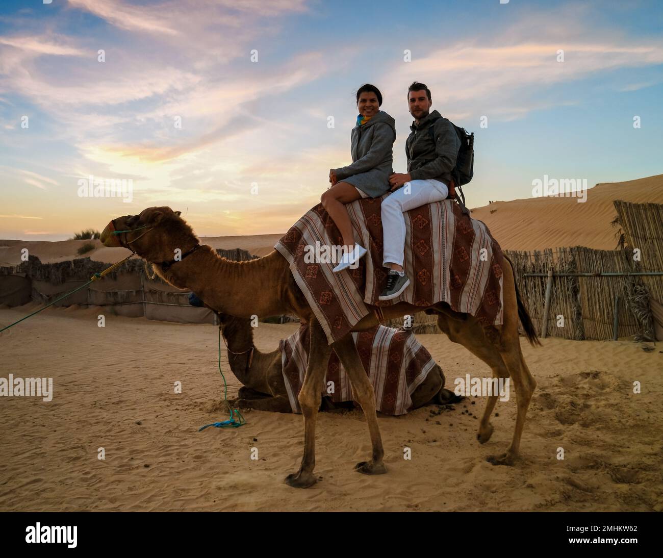 Couple riding a camel during Dubai desert safari at the safari camp ...