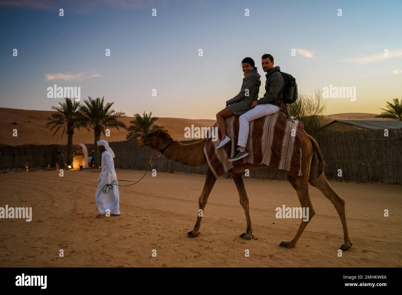 Couple riding a camel during Dubai desert safari at the safari camp ...