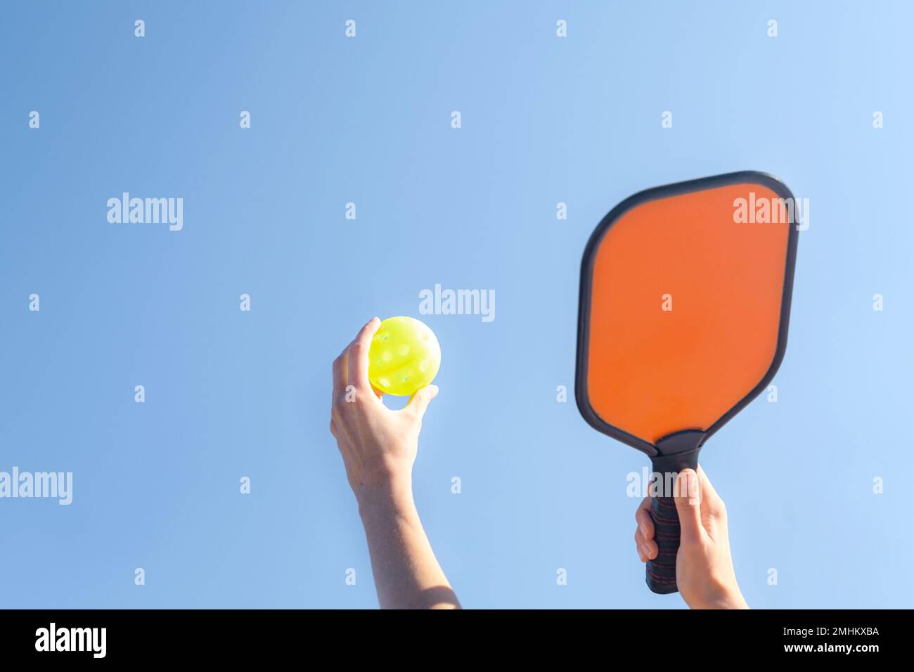 pickleball game, hands over blue sky hitting pickleball yellow ball ...