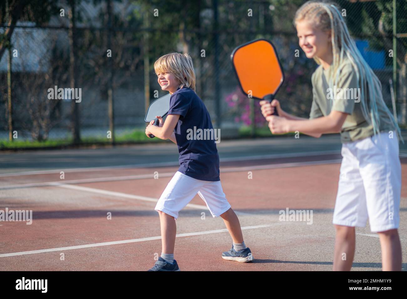 Laughing boy and girl playing pickleball game, hitting pickleball ...