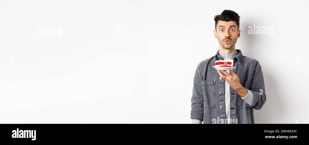 Handsome birthday guy blowing candle on cake and making wish, looking ...