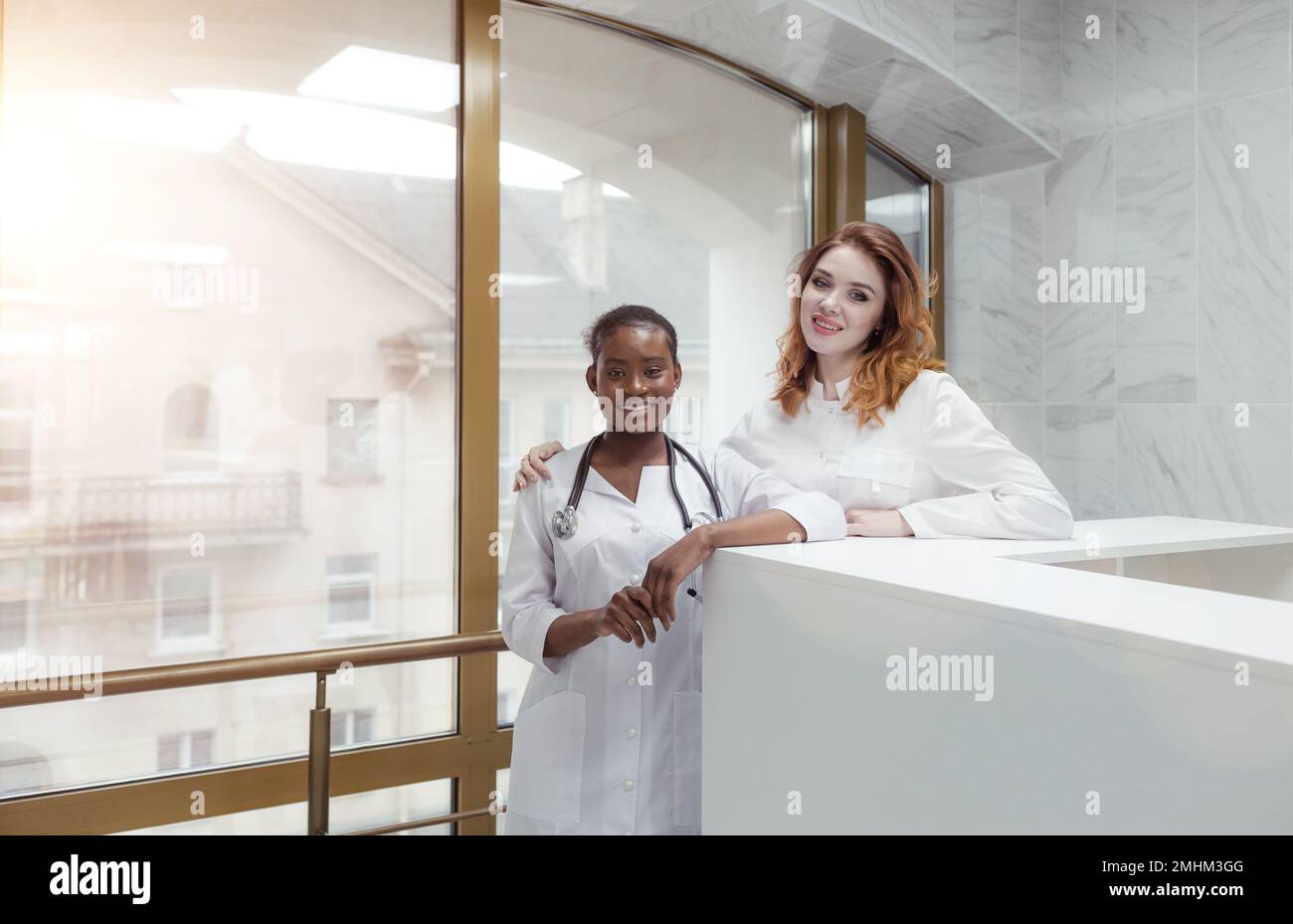 two beautiful female doctors smile at the reception desk at the ...