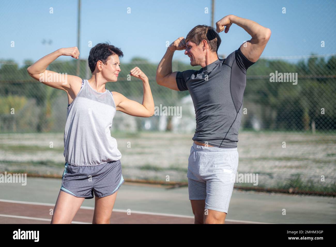 Athletic couple checking their muscles Strong biceps, doing sport ...