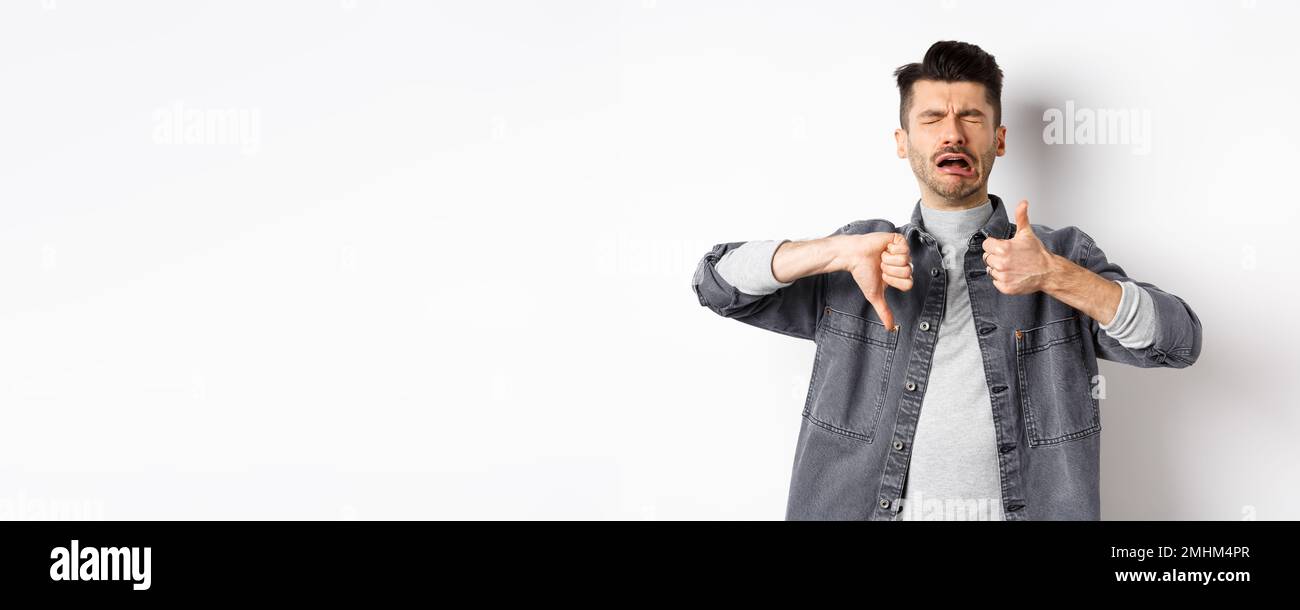 Sad man crying and showing thumbs up down, whining and complaining ...