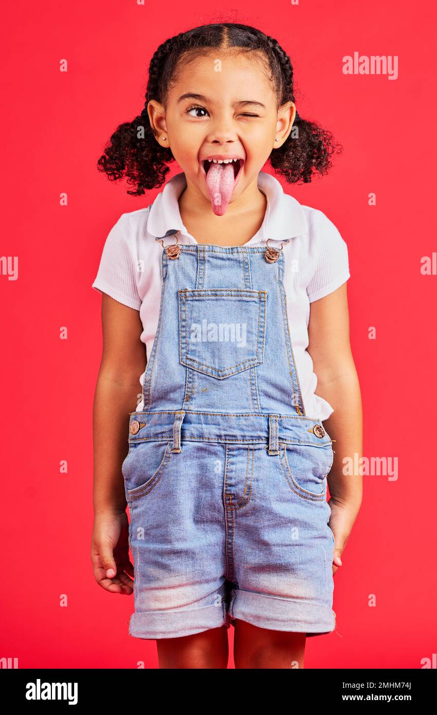 Child, face and tongue out on isolated red background in goofy, silly games and playful facial ...