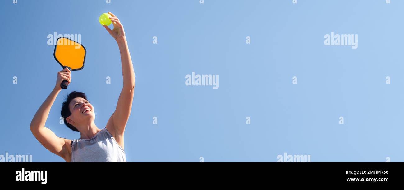 Pickleball banner over blue sky, woman playing pickleball game, hitting ...