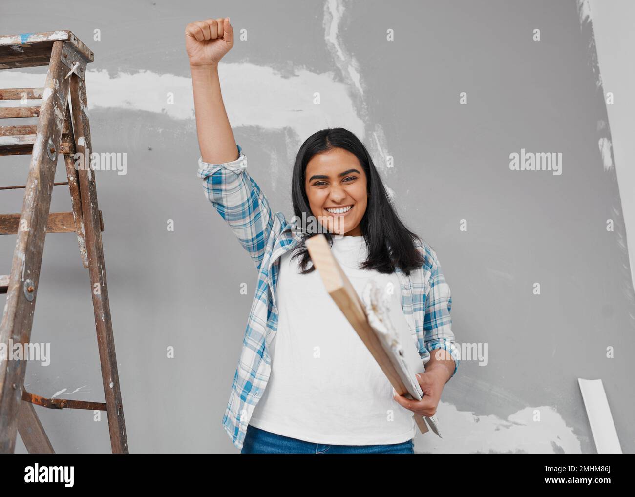Young Indian woman raises fist proud of DIY construction progress carry ...