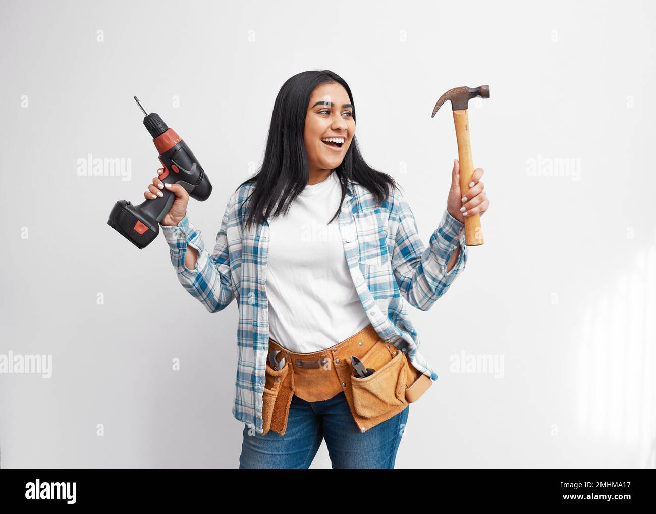 A strong young Indian woman holds a hammer and screwdriver as she ...