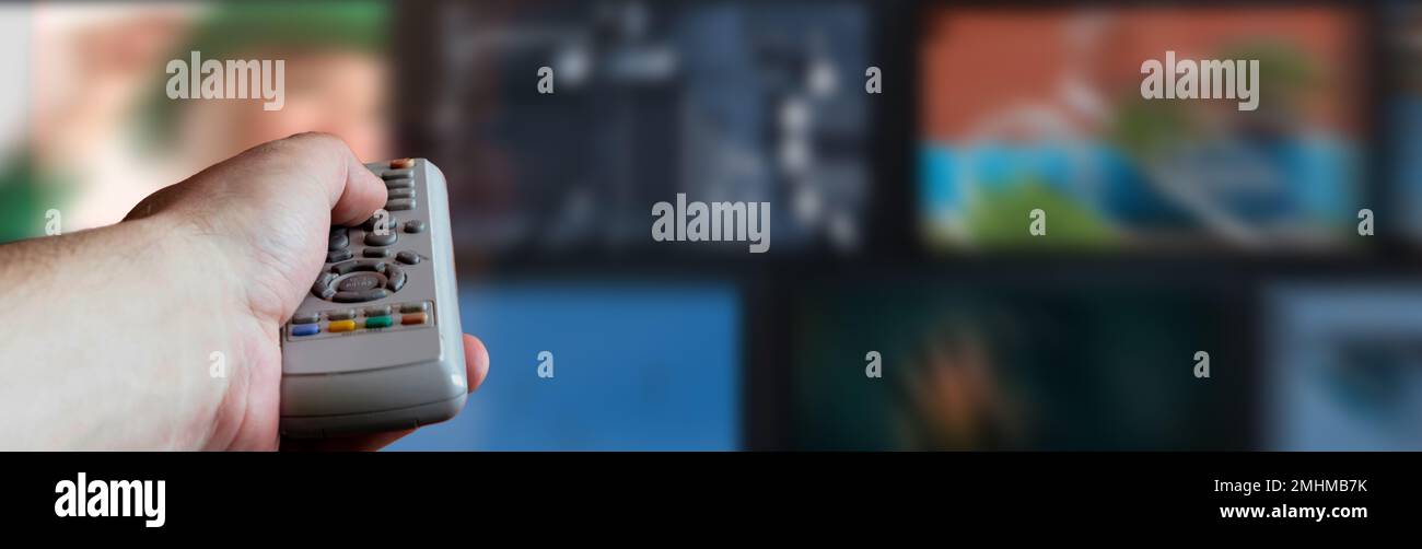 TV channels in background and remote control in hand. Television and ...