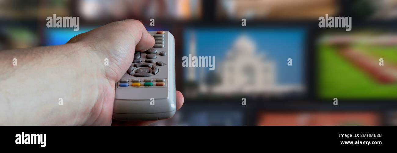 TV channels in background and remote control in hand. Television and ...