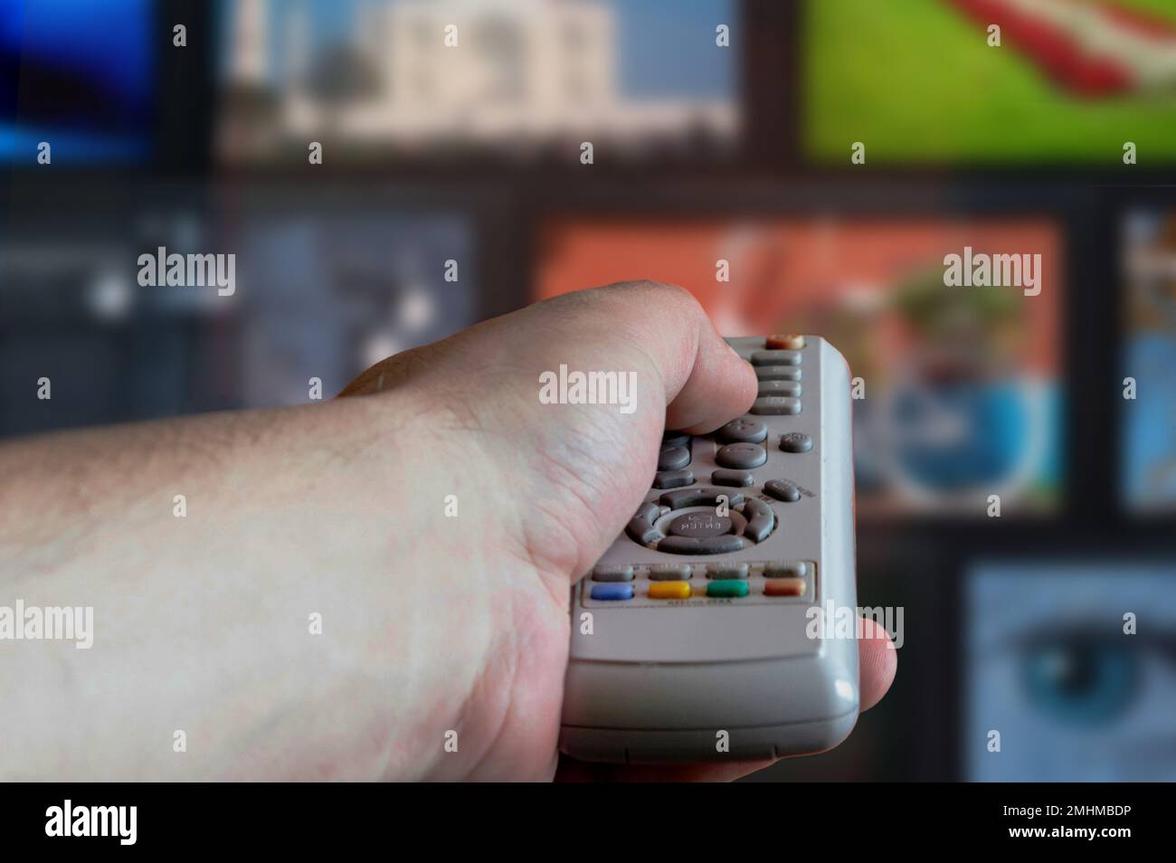 TV channels in background and remote control in hand. Television and ...