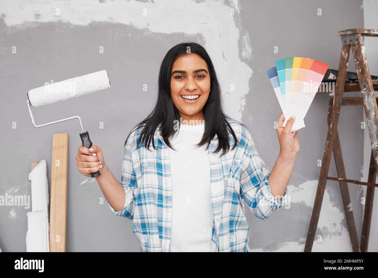 Young Indian woman poses with paint, brush, swatches getting ready to ...