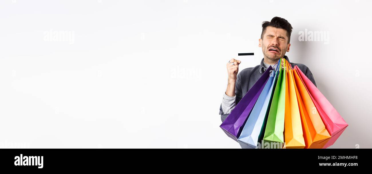Sad crying man wasted all money on shopping, holding bags and showing ...