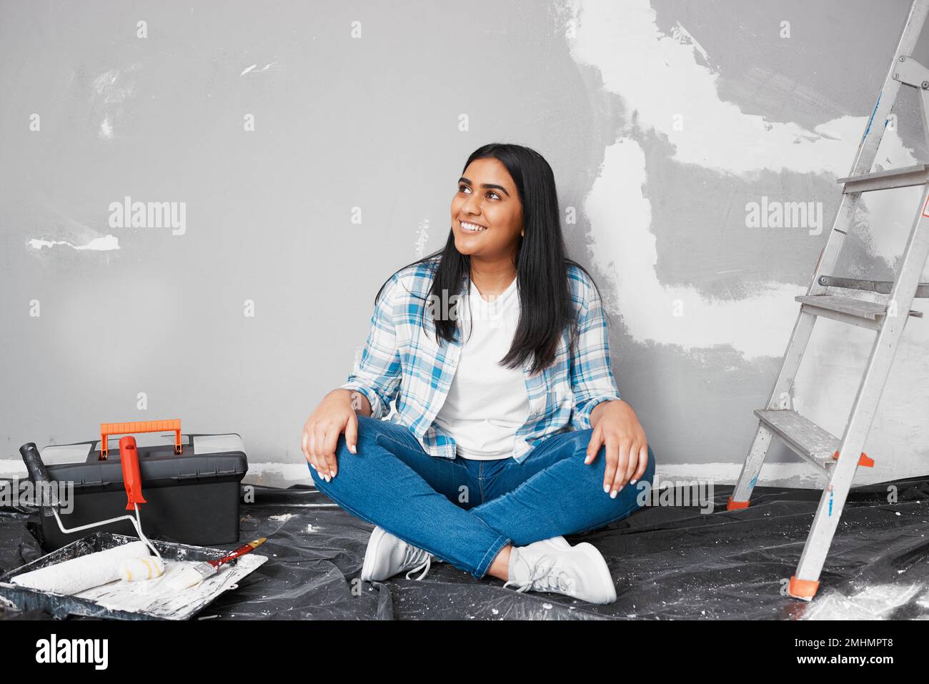 Young smiling Indian woman sits on floor taking a break home DIY Stock ...