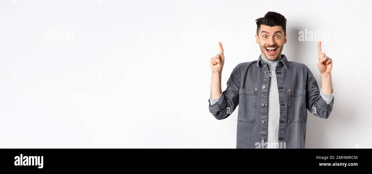 Excited handsome guy pointing fingers up, smiling happy and showing ...