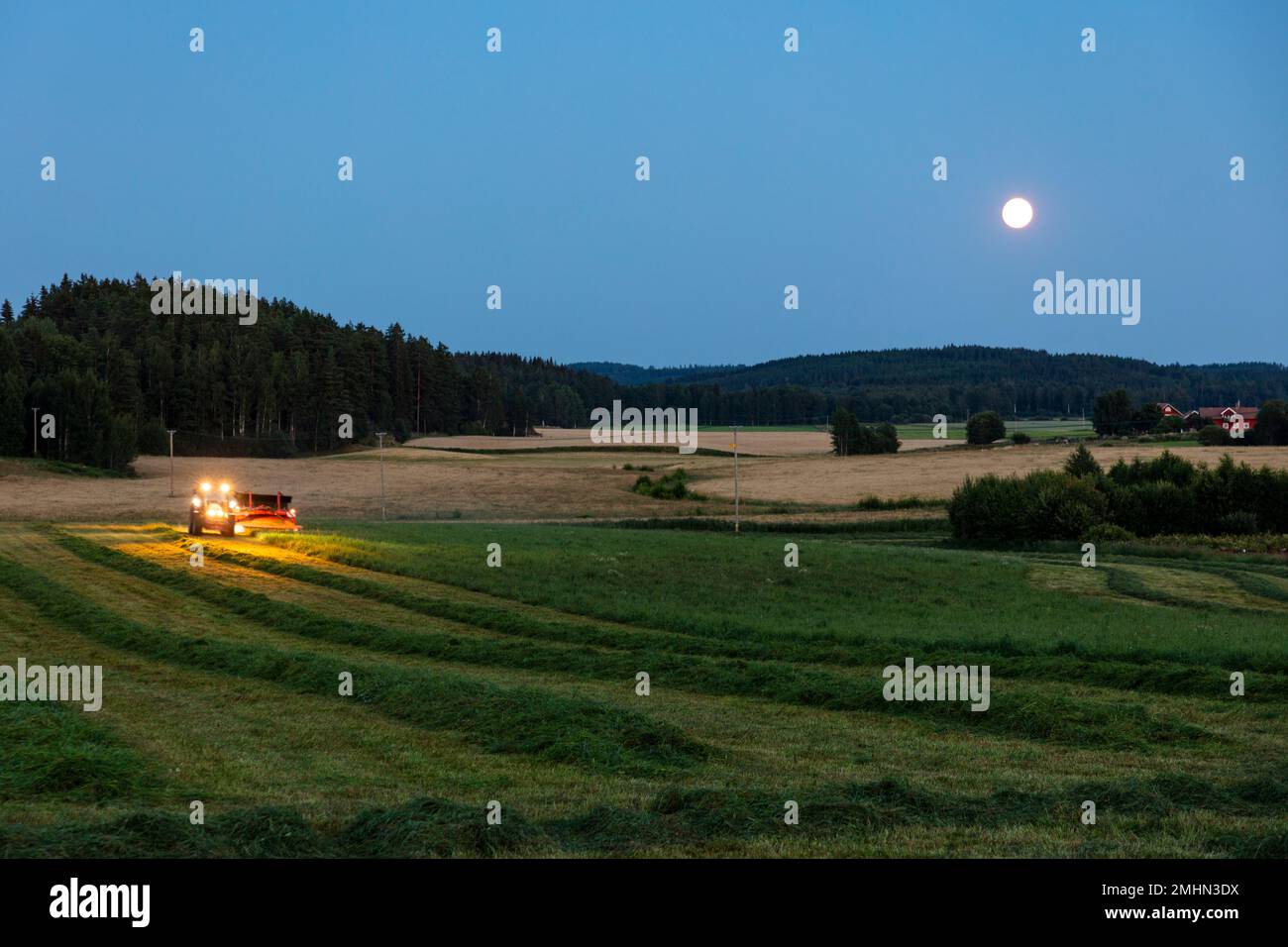 Farm machine working on farm at dusk Stock Photo - Alamy
