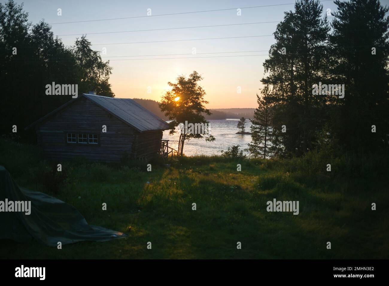 Wooden cottage by lake at sunset Stock Photo - Alamy