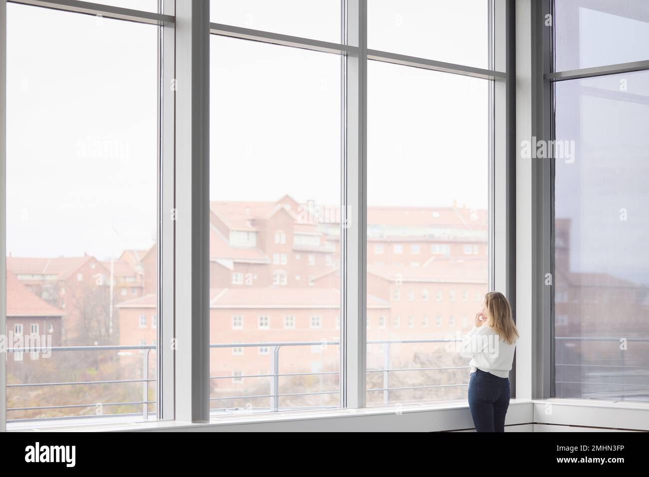 Woman looking through window Stock Photo - Alamy