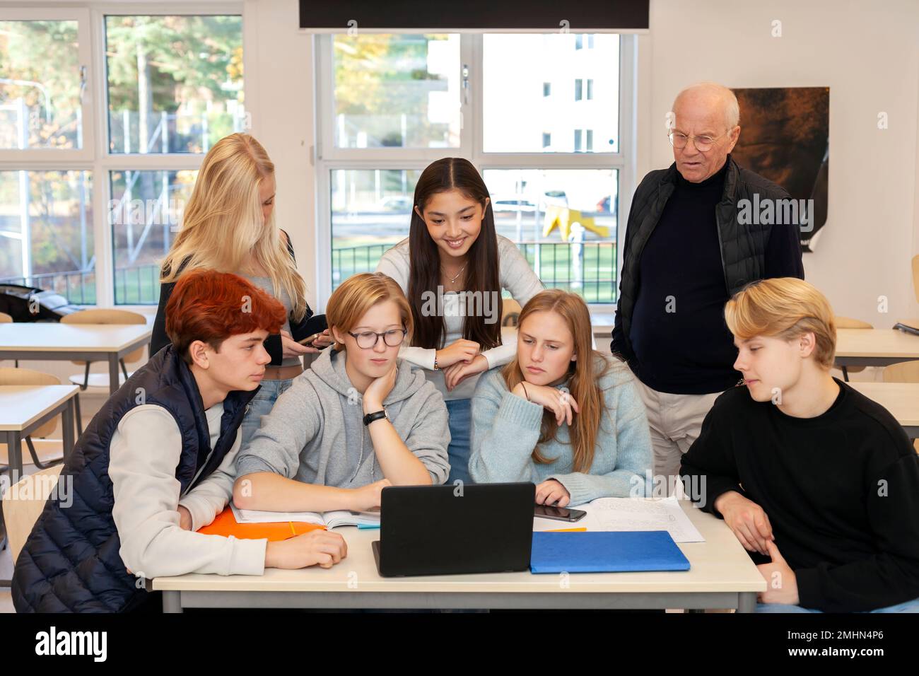 Teenage kids and teacher using laptop in classroom Stock Photo - Alamy