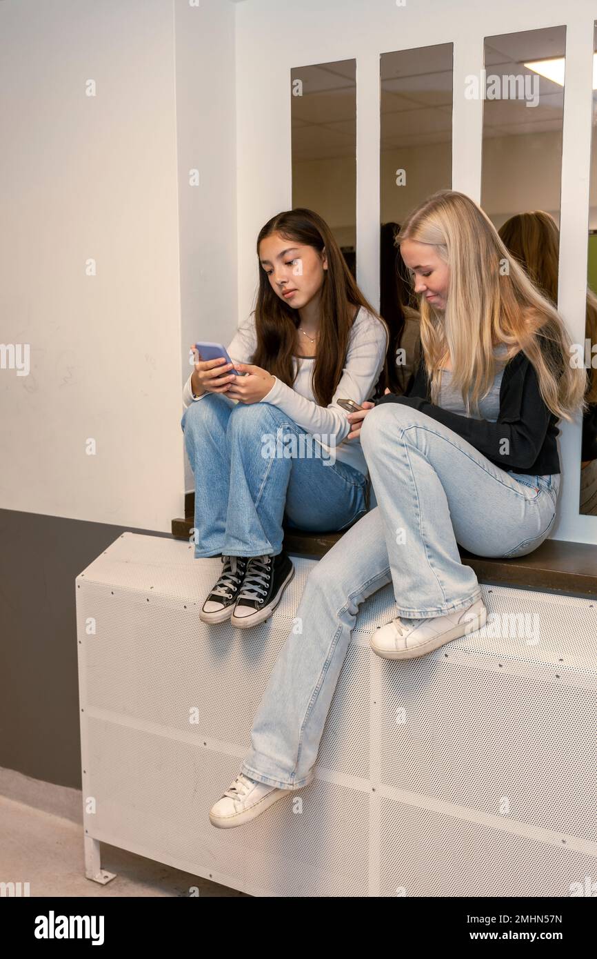 Teenage girls using phones at school Stock Photo - Alamy