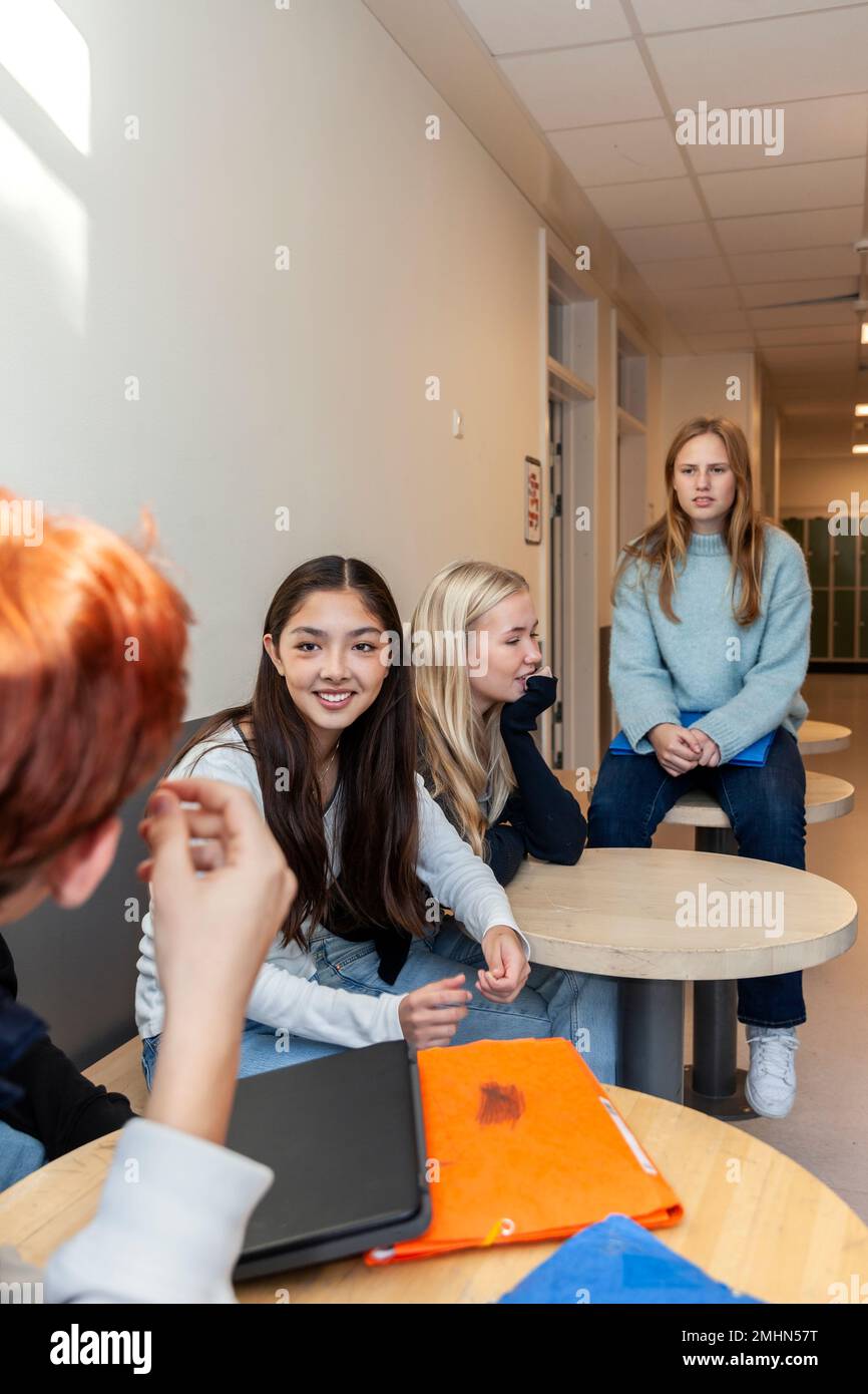 Teenagers sitting and talking on school corridor Stock Photo - Alamy